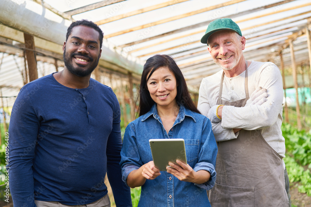 Smiling farmer with tablet PC amidst colleagues at farm Stock Photo ...