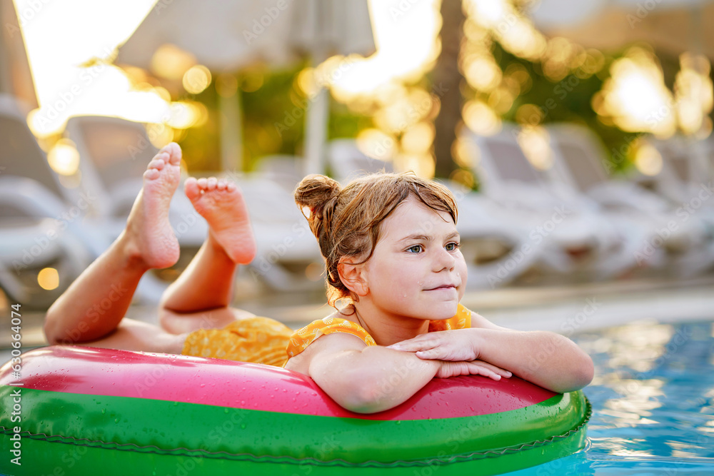 Happy little girl with inflatable toy ring float in swimming pool ...