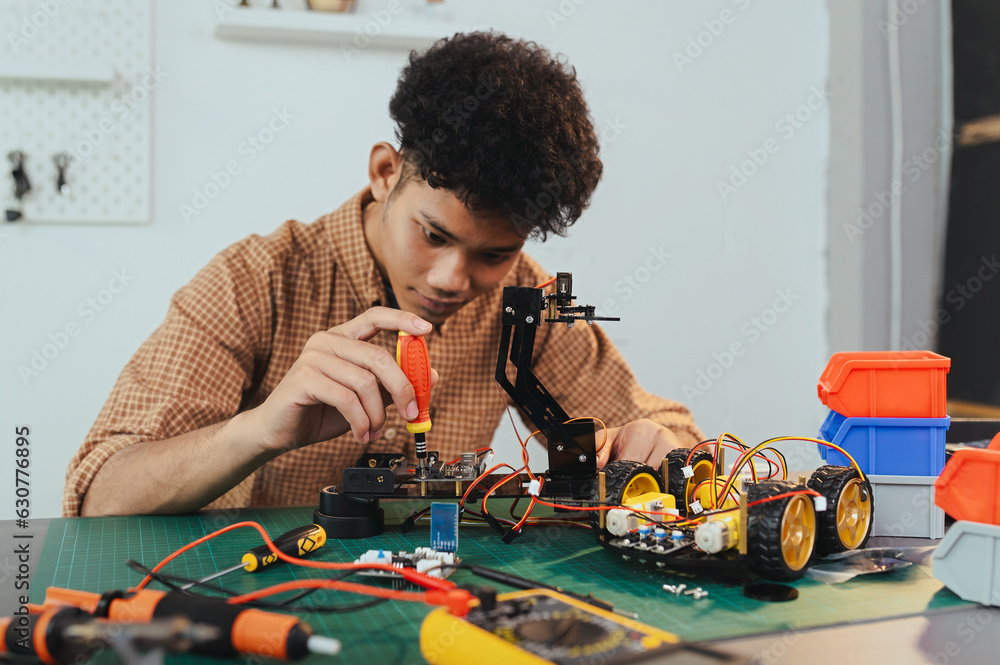 Asian young man assembling a robotic car, focus on robotics, assembling ...