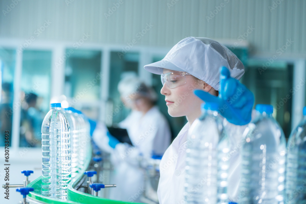 scientist worker checking the quality of water bottles on the machine ...