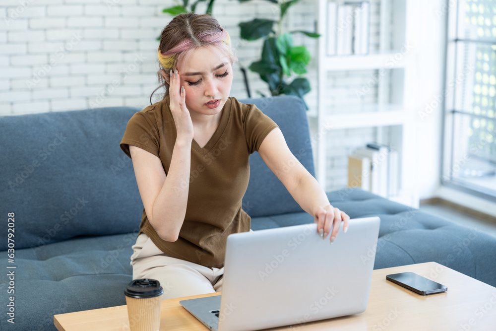 Young cute Asian Girl having a headache while studying and using laptop by raise the hands to ...