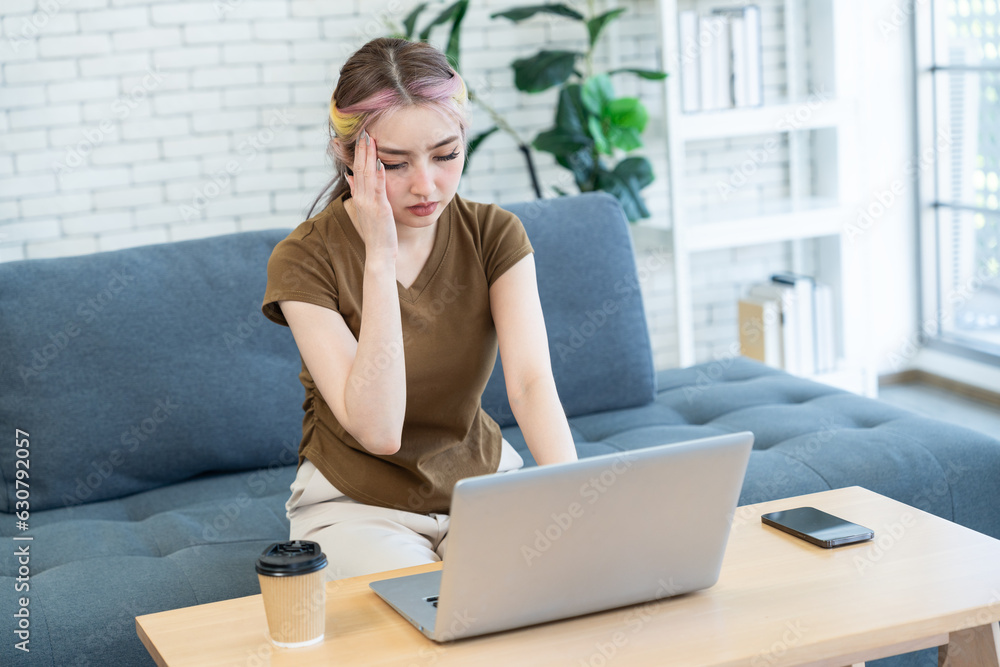 Young cute Asian Girl having a headache while studying and using laptop by raise her hand to ...