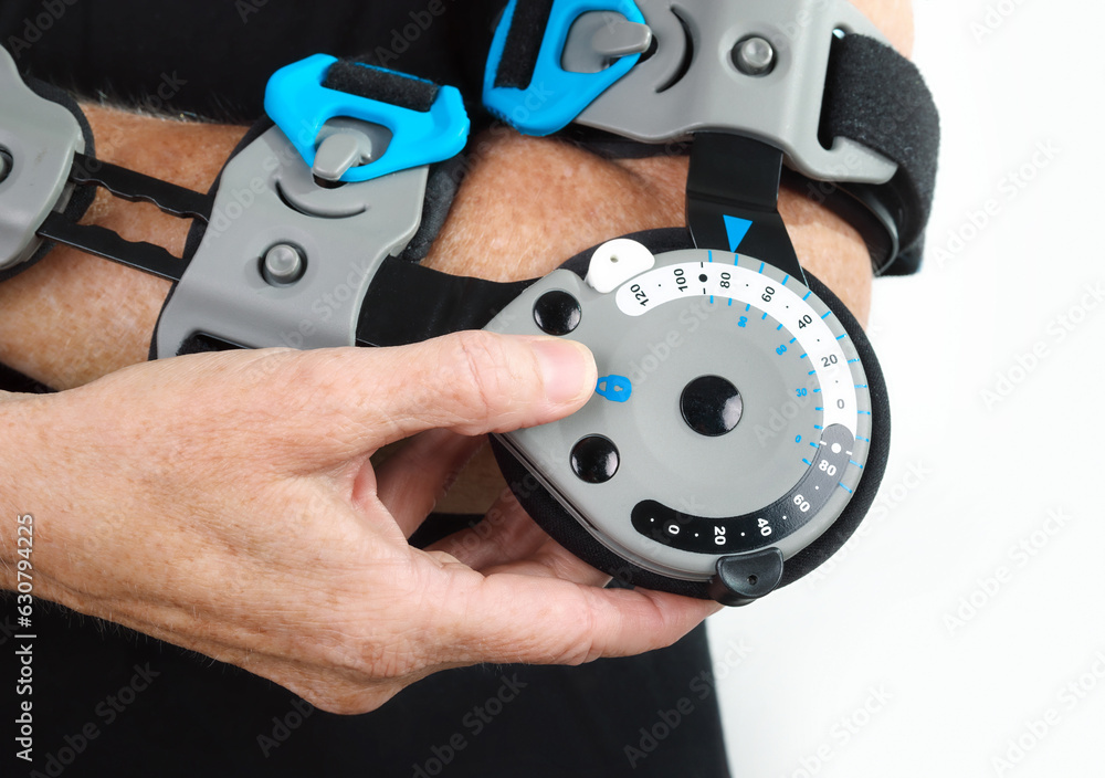 Woman with elbow brace or postoperative ROM brace. A person adjusting ...