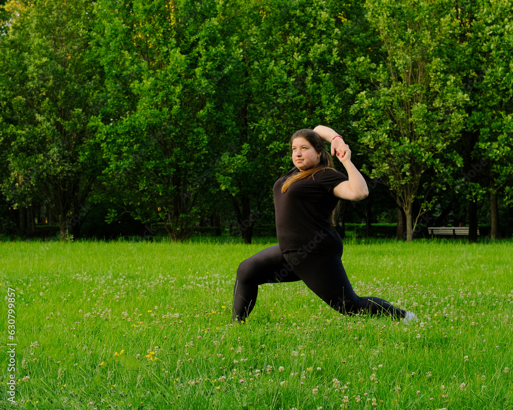 Fat girl doing fitness in the park. A plump girl does gymnastics. Warm ...