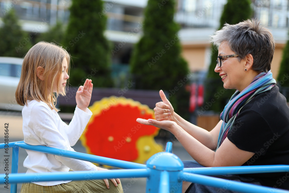 A woman and a child communicate with sign language. They are sitting on ...