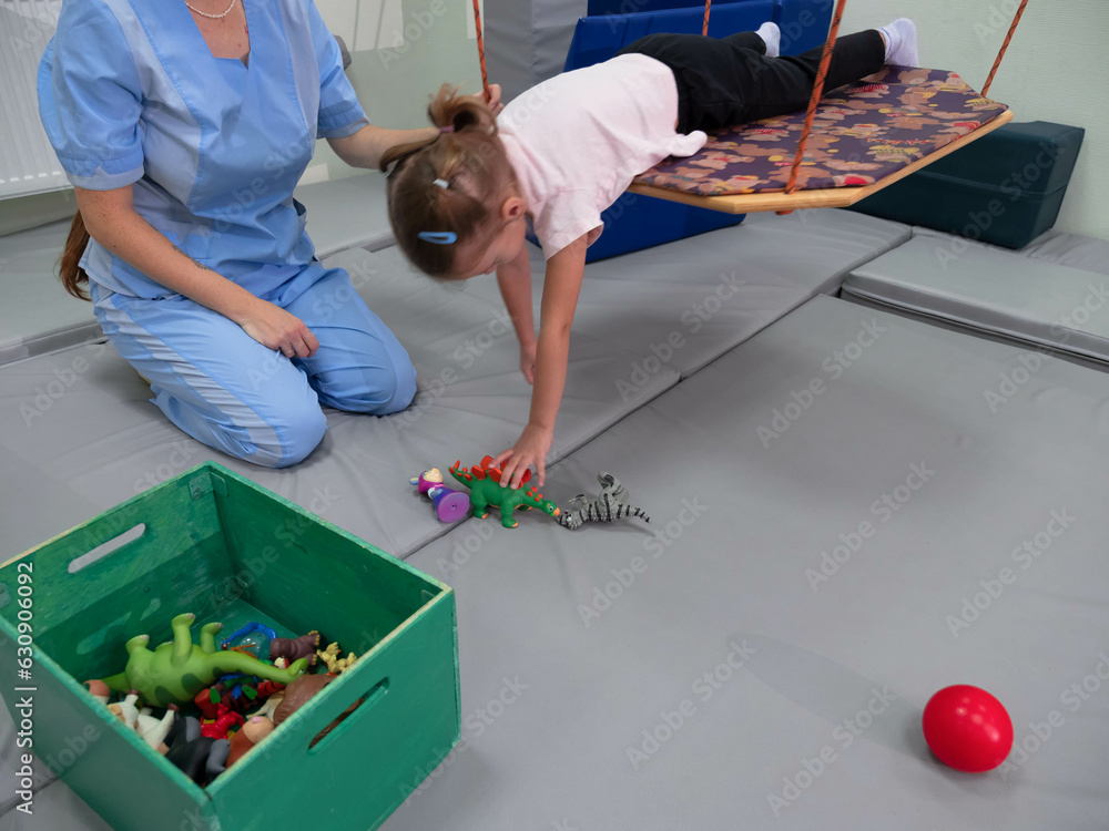 Child with physiotherapist on swing during sensory integration session ...
