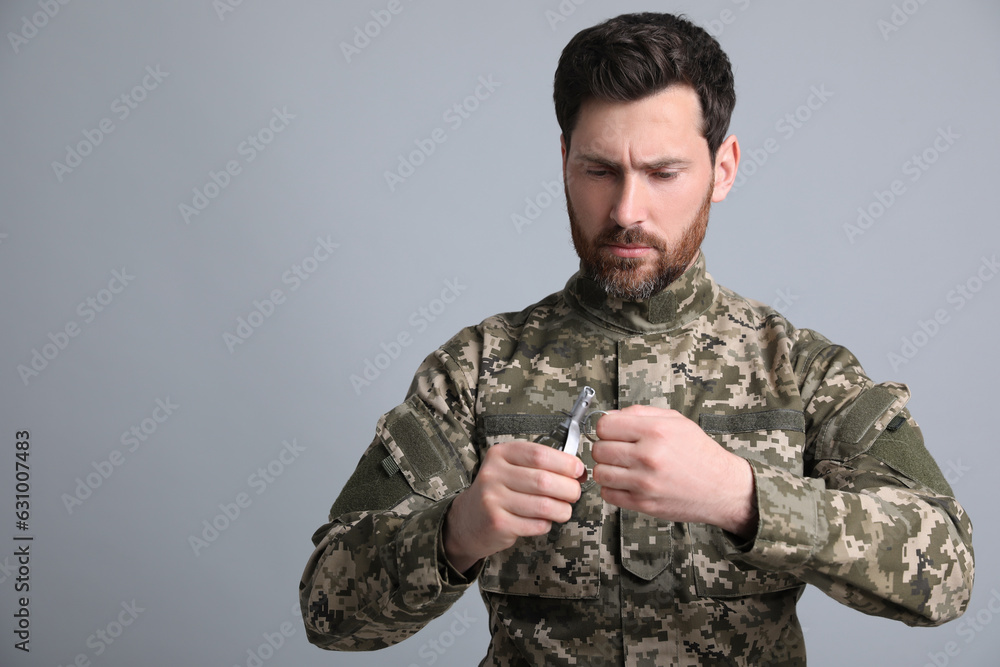 Soldier pulling safety pin out of hand grenade on light grey background ...