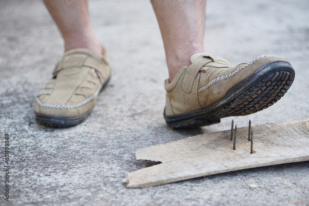 Closeup man wear shoes is stepping on rusty metal nail on wood. Concept ...