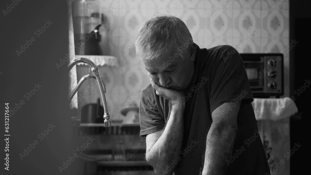 Senior man suffering from depression at home alone leaning by kitchen ...