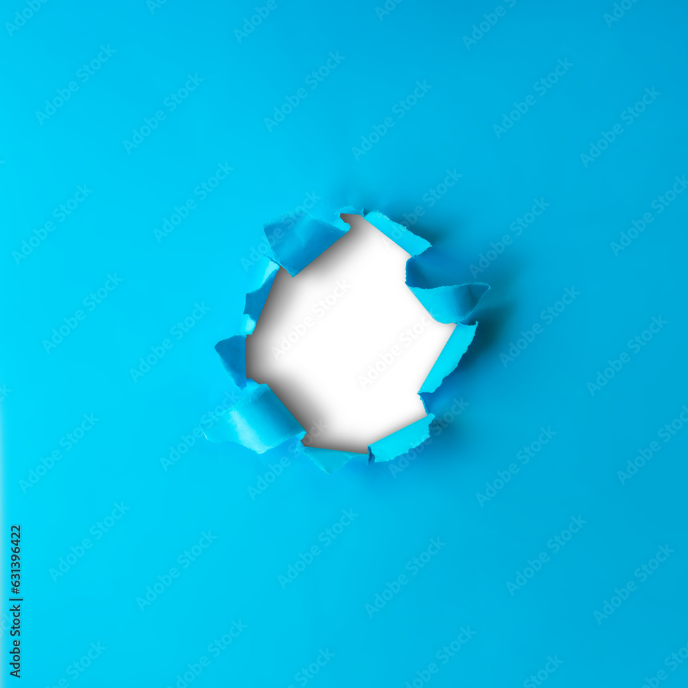 Torn hole in plain blue paper with a black background. Concept for ...