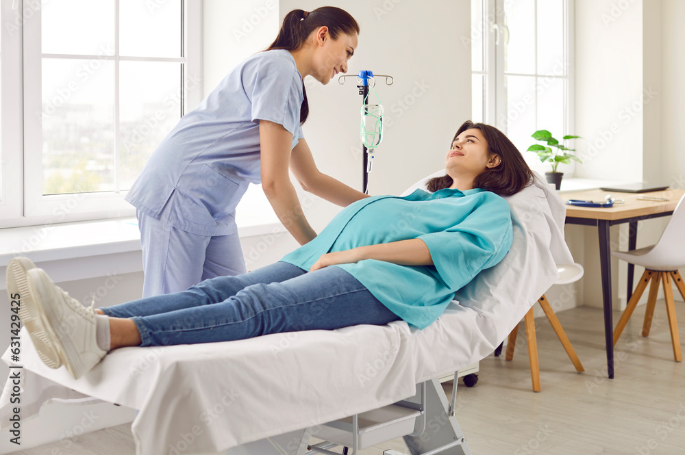 Young friendly nurse help pregnant woman in receiving IV drip infusion ...