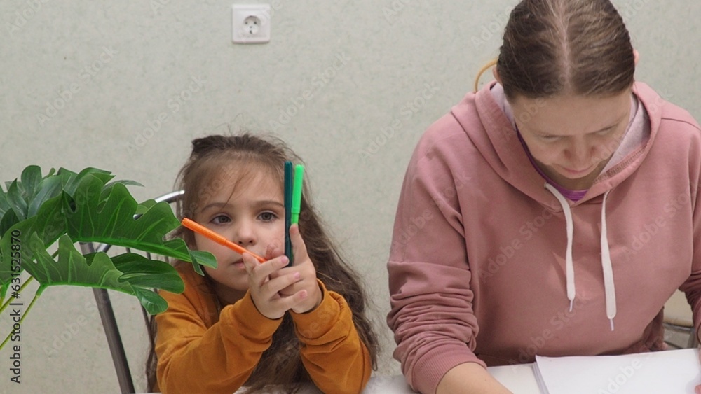 Little girl taking online art class with mother helping her at home ...