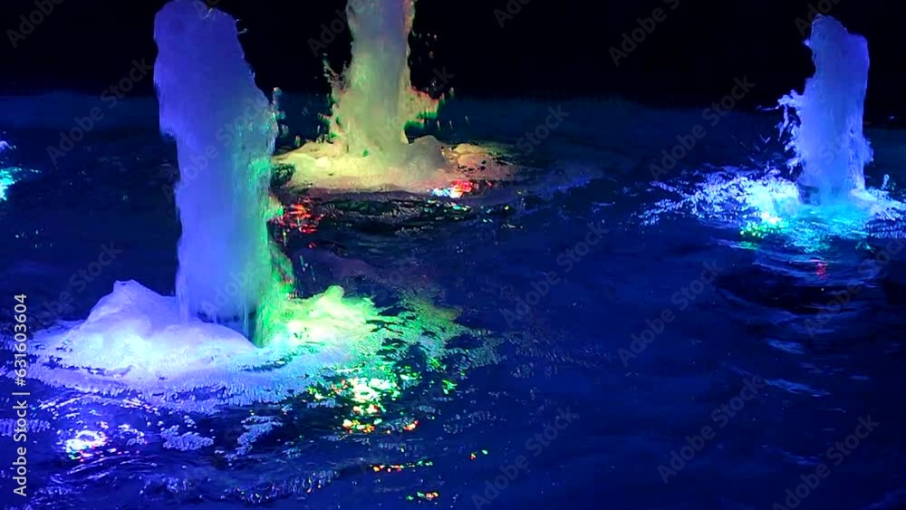 Fountain in water illuminated by colorful lights at night. Flow of ...