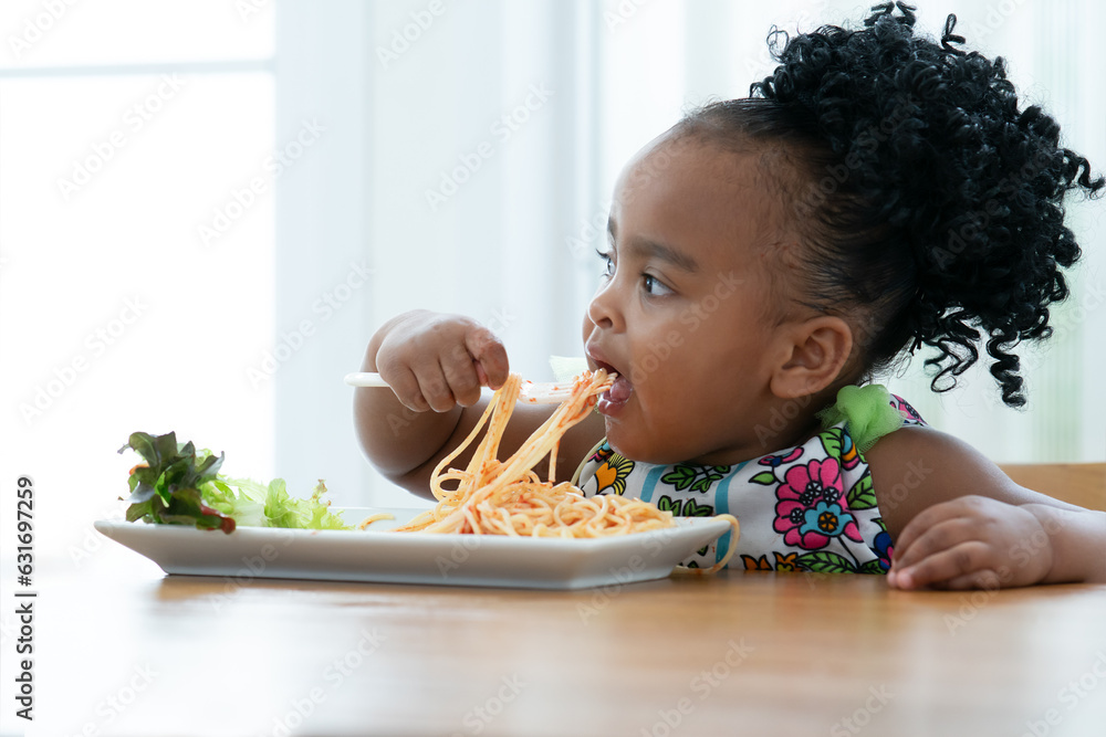 Portrait of little African toddler girl eating spaghetti tomato sauce ...