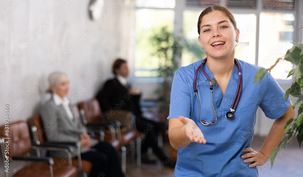 Cheerful friendly young female doctor in blue uniform making welcome ...