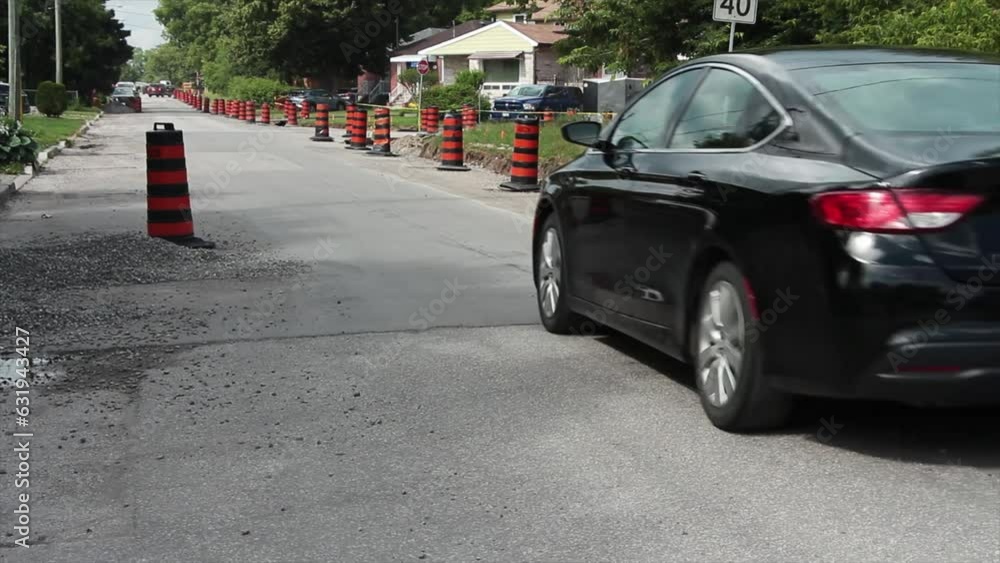 long line row of orange and black traffic delineator pylon barrel drums ...