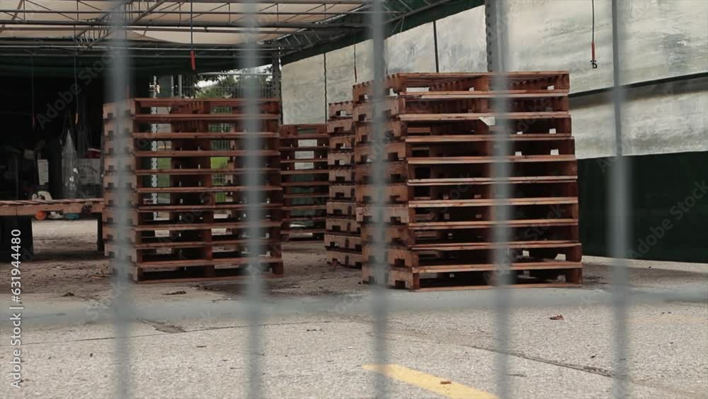 piles of wood palettes skids on pavement in outdoor canopy tent ...