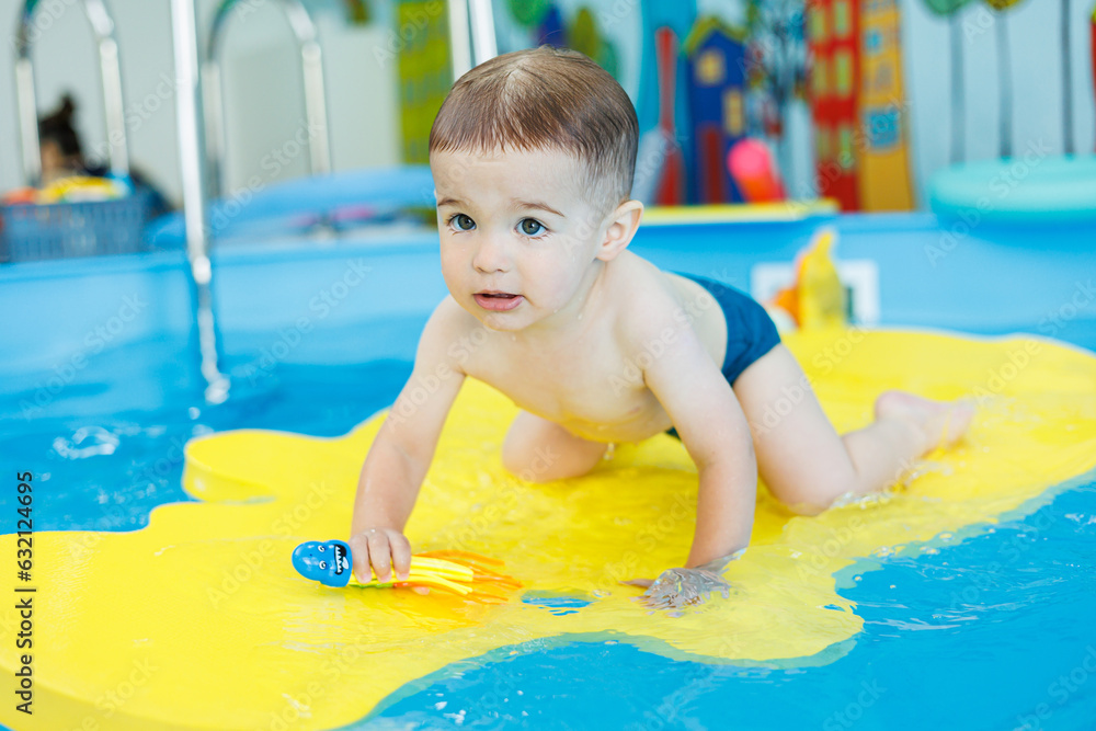 Development for babies. A little boy is learning to swim in the pool ...