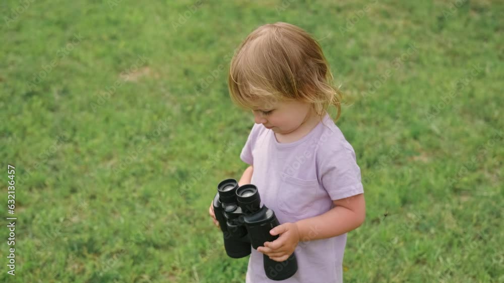 Little girl using binoculars in a forest. 2 years kid looking ahead ...