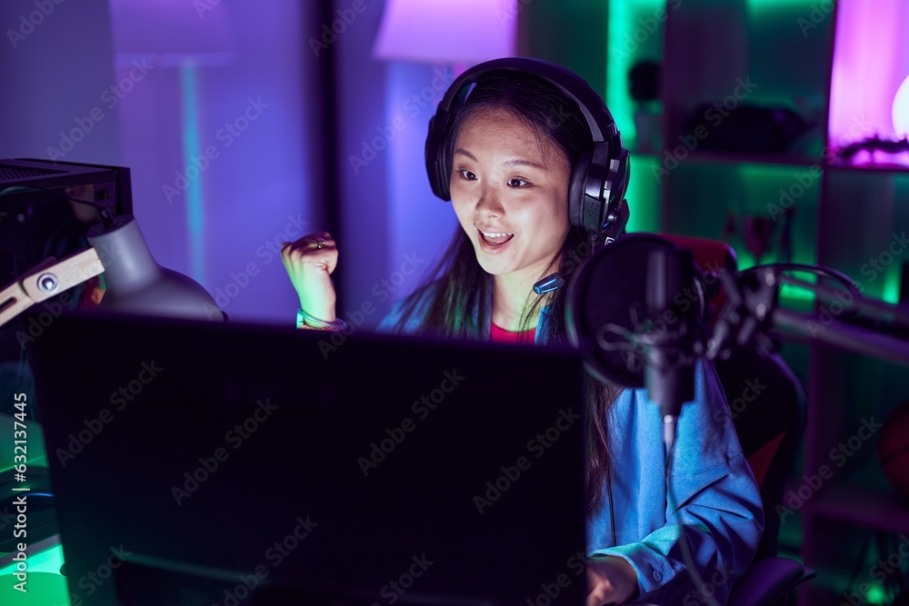 Young asian woman playing video games pointing thumb up to the side ...