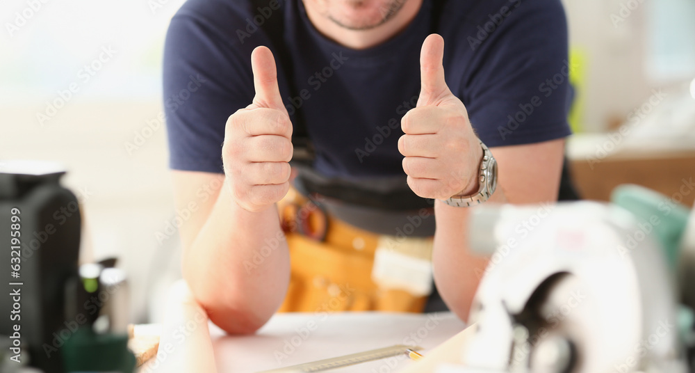 Smiling worker in yellow helmet show confirm sign with thumb up at arm ...
