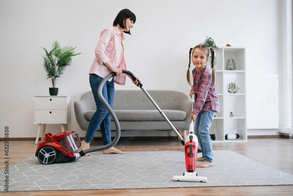Poster Full length view of preteen girl holding upright vacuum cleaner ...