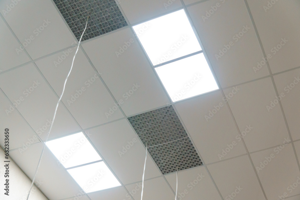White suspended ceiling with square fluorescent lights in an office ...