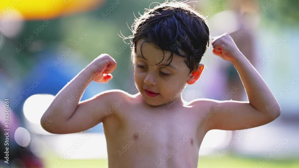 One adorable little boy flexing muscles sitting on grass outside after ...