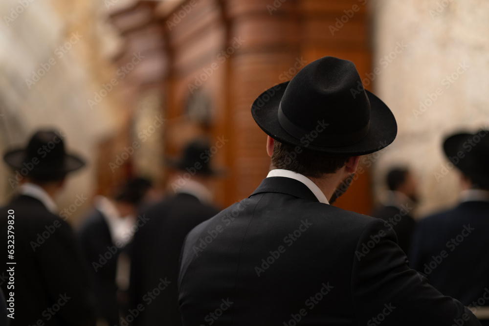 Jewish men in traditional Haredi clothes pray alongside a Torah ark at ...