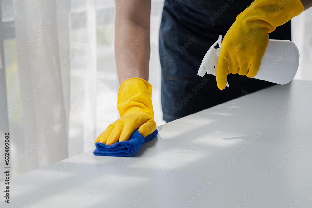 Person cleaning the room, cleaning staff is using cloth and spraying ...