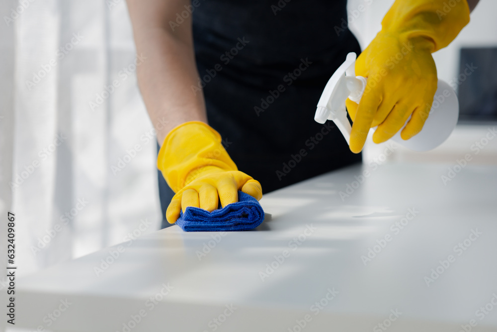 Person cleaning the room, cleaning staff is using cloth and spraying ...
