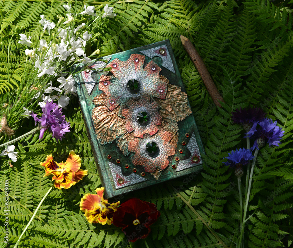Still life with beautiful magic book of spells and flowers against ...