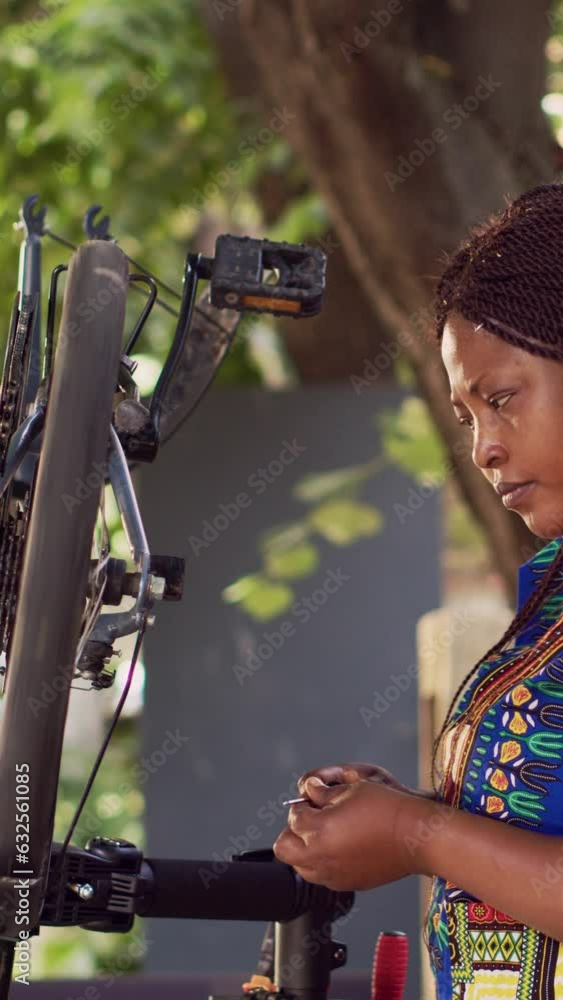 Vertical video Determined female cyclist using specialized work tool to ...