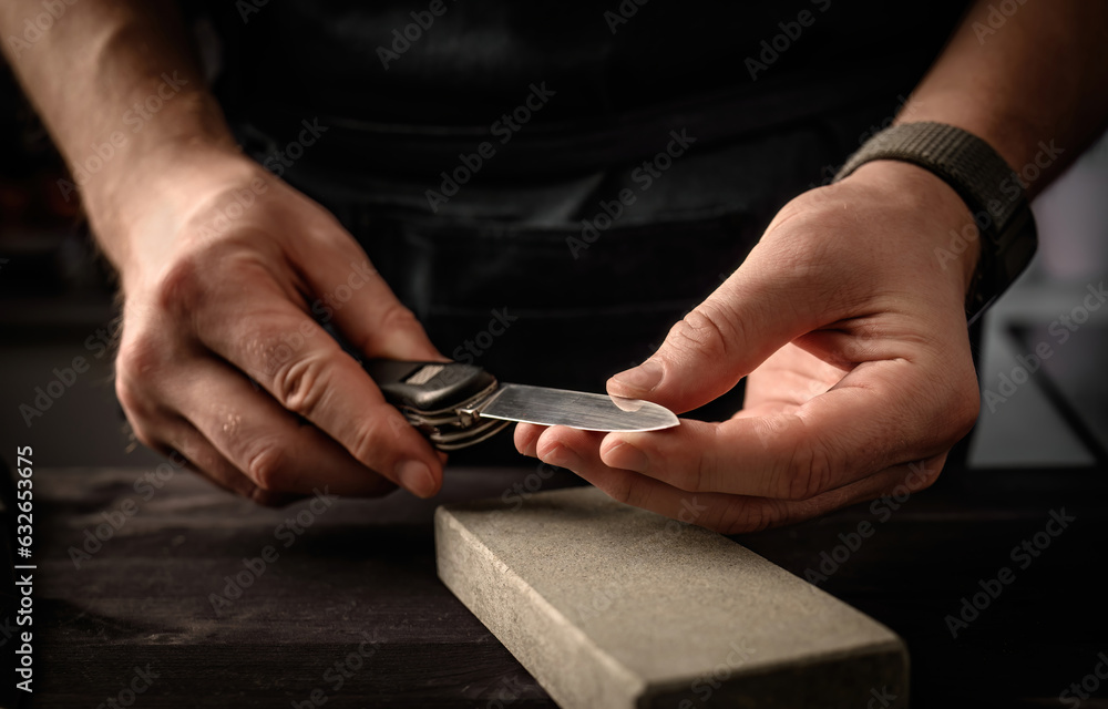 Man's hands with folding knife and sharpen stone tool. master ...