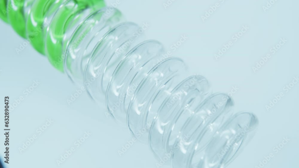 Green liquid flows down a glass spiral pipe. Test tube with spiral pipe ...