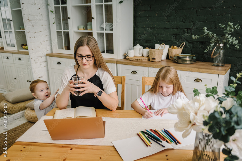 Mother working with kids at home. Woman working, learns on laptop ...
