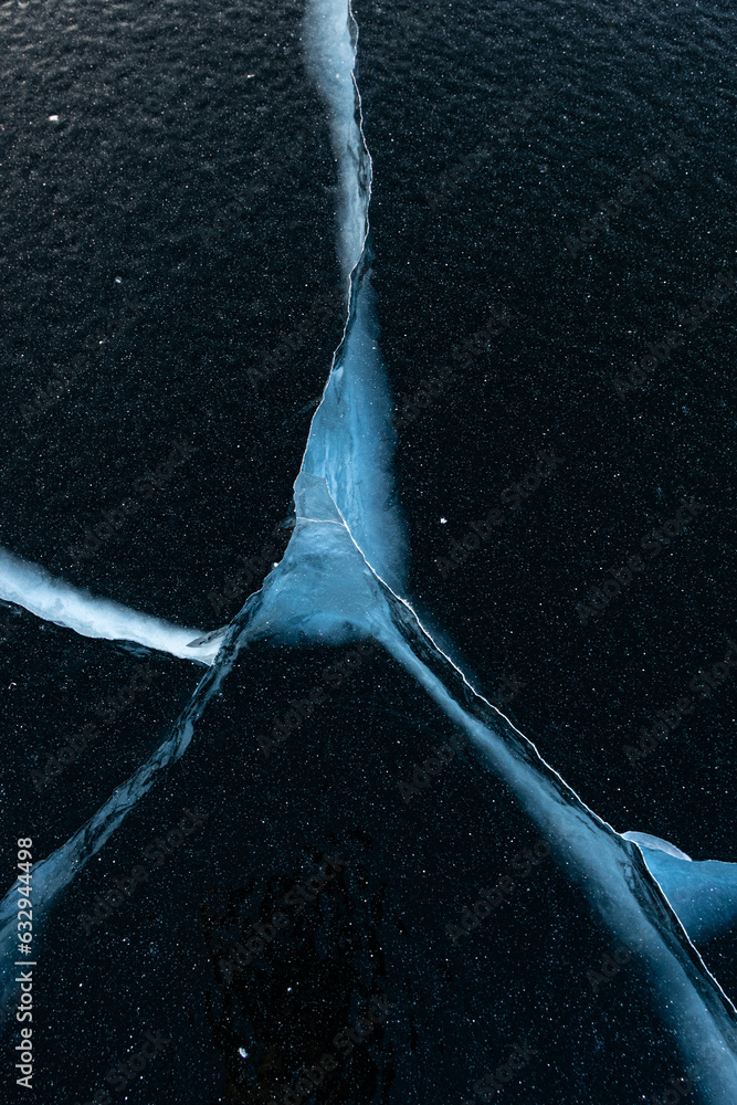 The cracked ice background. Blue transparent ice deep cracks top view ...