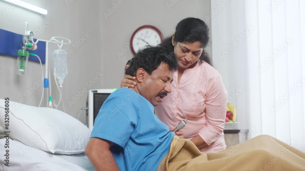 Caring Indian wife helping sick husband to get up from bed while ...