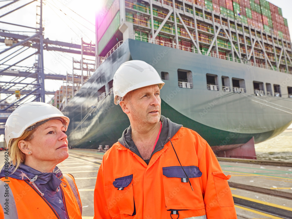 Portrait of docks worker and manager talking infront of cargo ship and ...
