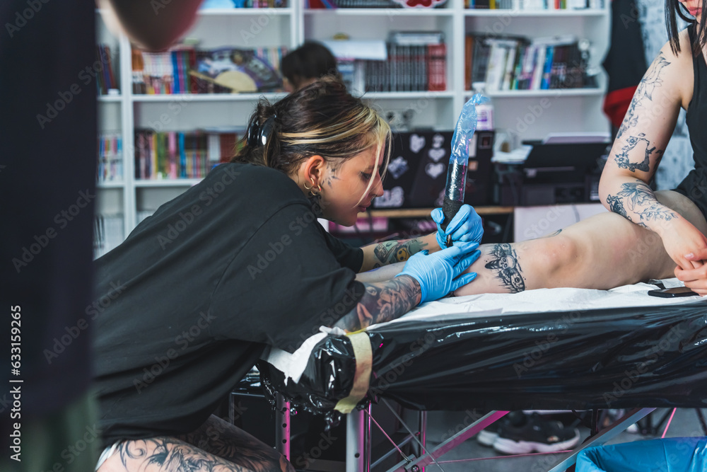 Busy day at tattooing studio. Female artist sitting on a chair and ...