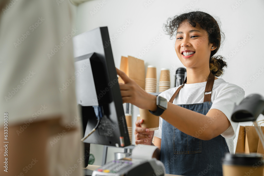 Happy young Asian woman cashier wears an apron and using pos terminal ...