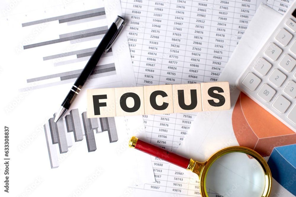 FOCUS text on wooden block on graph background with pen and magnifier ...