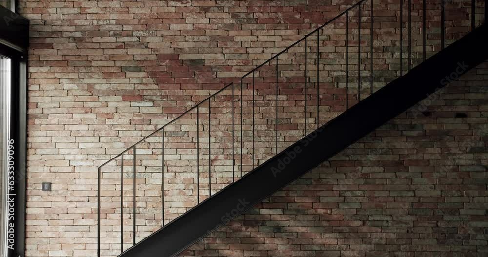 Old brick wall of brown color in a modern apartment with black stair ...