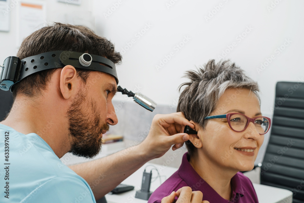 Otolaryngologist doing checkup of mid aged woman at modern medical ...