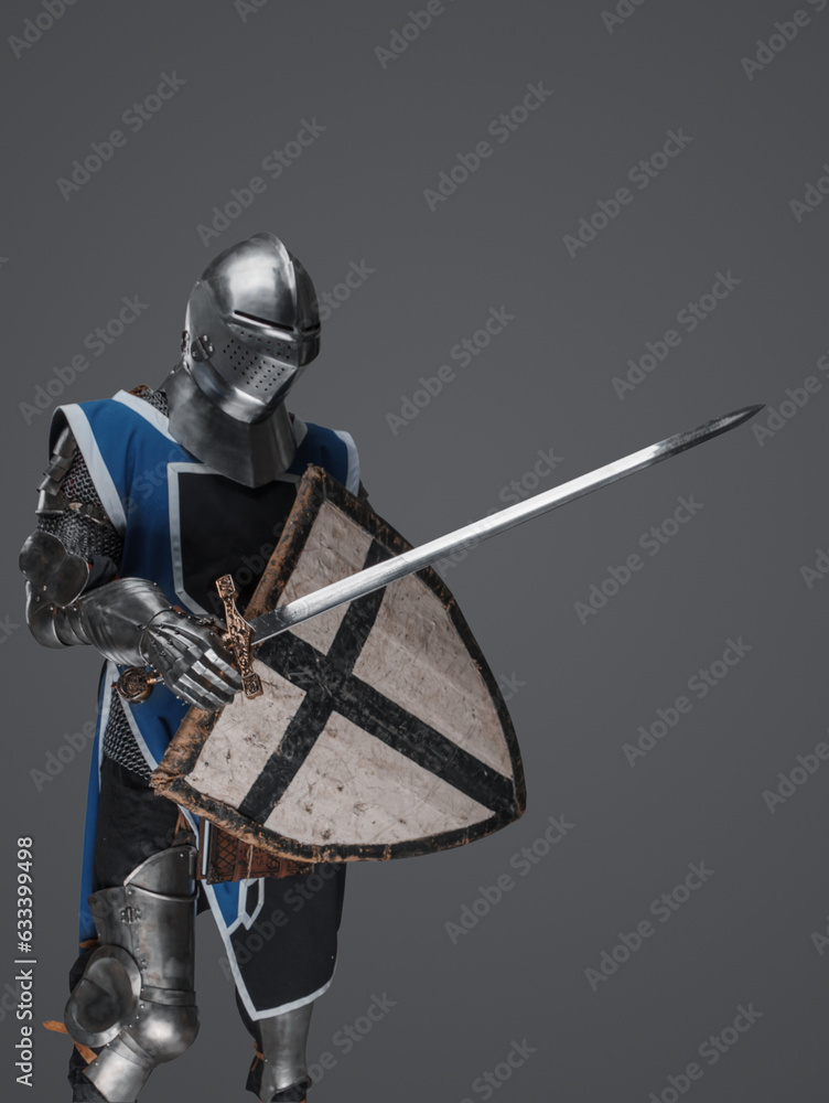 Blue surcoat-wearing medieval knight actively swinging sword in battle ...