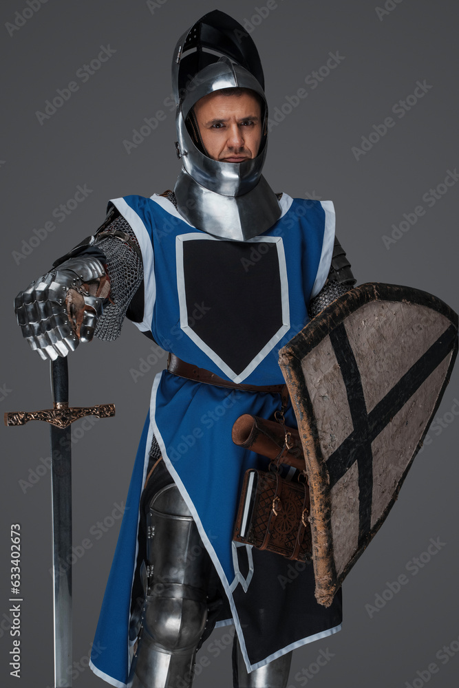 Valiant medieval warrior wearing armor and blue surcoat with raised ...