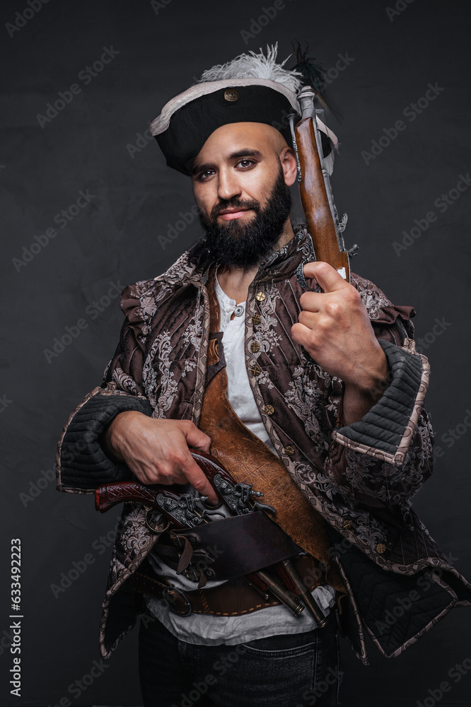 Pirate with a black beard holding two muskets, dressed in a vest and ...