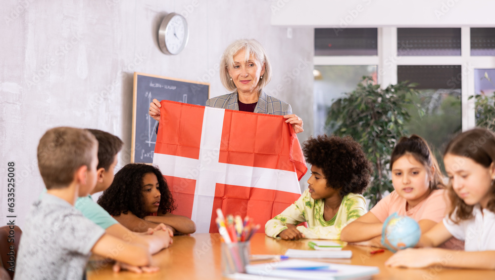 High school female teacher, conducting a lesson in the classroom, holds ...