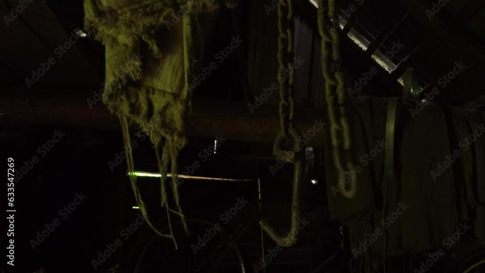 Rusty chains hang from the ceiling and dangle in an abandoned basement ...
