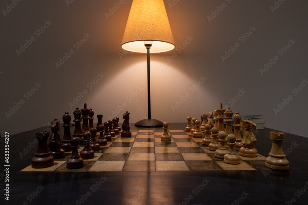 A lamp by a chessboard casts a warm glow over the intricate chess ...
